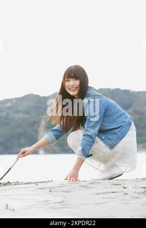 Japanese woman scribbling on the beach Stock Photo - Alamy