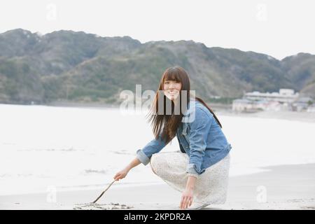 Japanese woman scribbling on the beach Stock Photo - Alamy