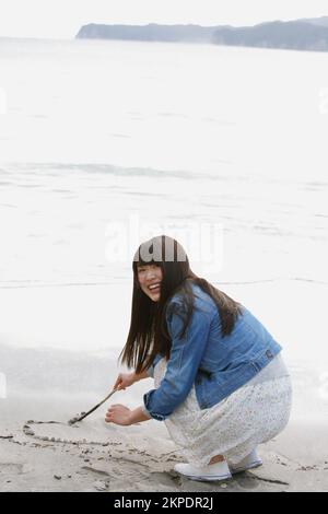 Japanese woman scribbling on the beach Stock Photo - Alamy
