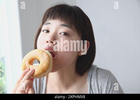 Young Japanese woman eating a donut Stock Photo - Alamy