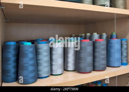 Sewing thread cones of different shade of colors on shelf in sewing ...