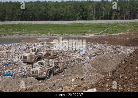 Landfill compactors spreading out and compacting discarded debris and ...