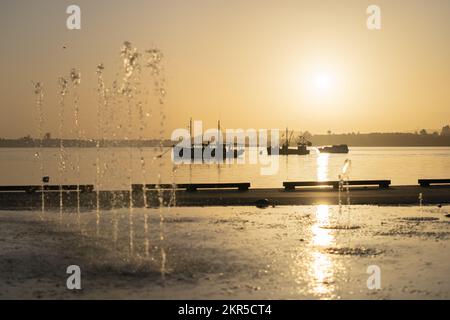Focus on-water fountain spurts water in air against golden hue of ...