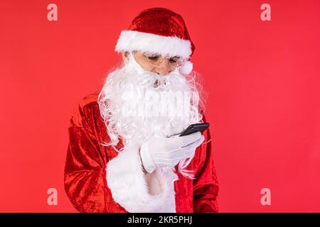 Man dressed as Santa Claus, consulting his mobile phone, on red ...