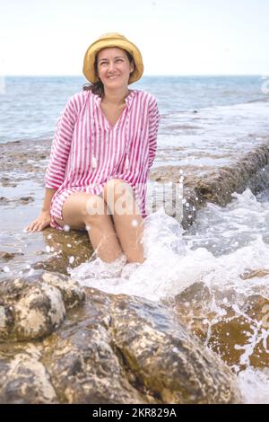 Woman splashes water while sitting on blue float in pool surrounded by ...