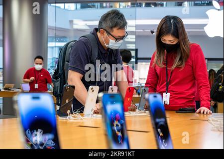 An employee assists a customer with purchasing an Apple iPhone 14 at ...