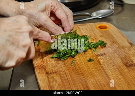Chef cuts fresh basil leaves on a wooden board for cooking Stock Photo ...