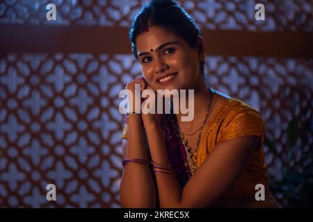 Portrait of smiling married Gujrati woman sitting on deewan and looking ...