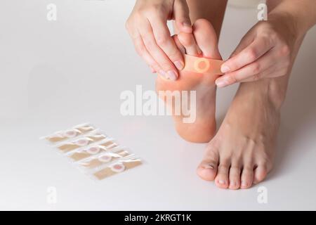 A girl sticks a medical plaster for plantar warts on her leg. Callus ...