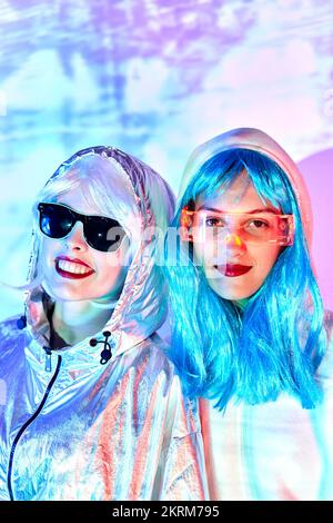 Smiling women in cyberpunk clothes and hoods against glowing neon ...