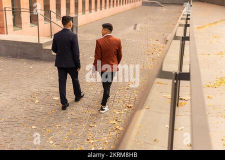 From above Hispanic men strolling on walkway near fence while greeting ...