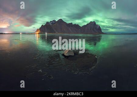 Breathtaking polar light shining over rough stony formation near icy ...