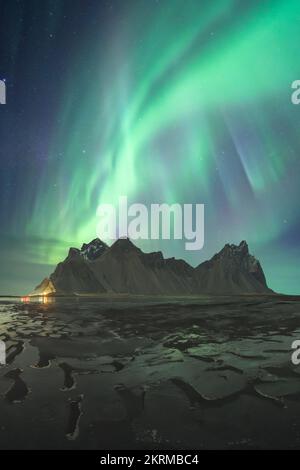 Breathtaking polar light shining over rough stony formation near icy ...