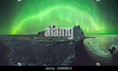 Breathtaking polar light shining over rough stony formation near icy ...