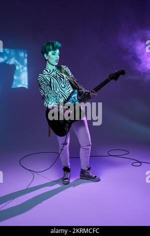 Female musician in trendy outfit and sunglasses playing electric guitar ...