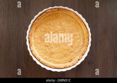A blind baked shortcrust pastry case in a white ceramic flan tin ...