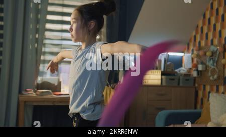 Young asian girl dances with gymnastic ribbon, showing vertical leg ...