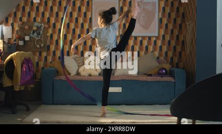 Young asian girl dances with gymnastic ribbon, showing vertical leg ...