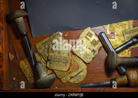 Handmade gold watch blanks on wooden table, metal engraving tools ...