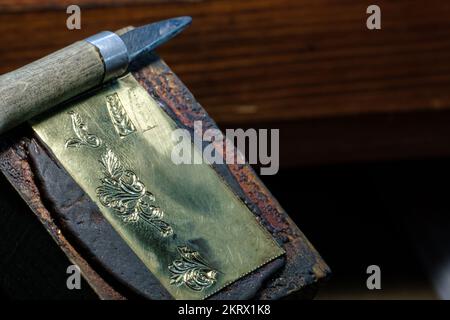 Handmade gold watch blanks on wooden table, metal engraving tools ...