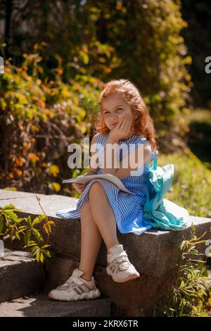 Long-haired girl holding a book in hands and smiling Stock Photo - Alamy