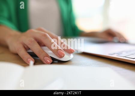 Employee holds computer mouse in her hand while working at office desk ...