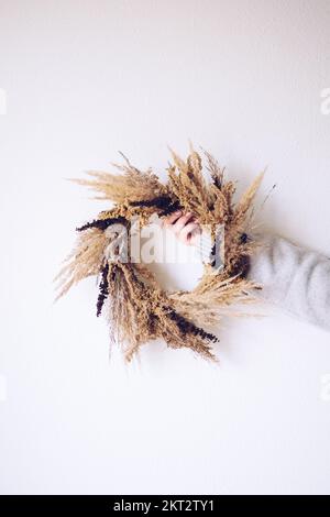 Woman making stylish autumn boho wreath with dry grass and wildflowers ...