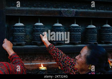 Devotees spin prayer wheels after the idol of Deity Rato Machindranath ...