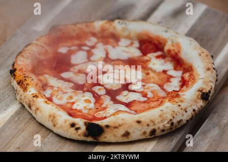 Hot pizza Margherita ready to eat with tomato sauce and mozzarella on a ...