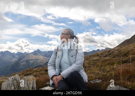Woman resting on a stone on a steep mountain path, austrian alps. High ...