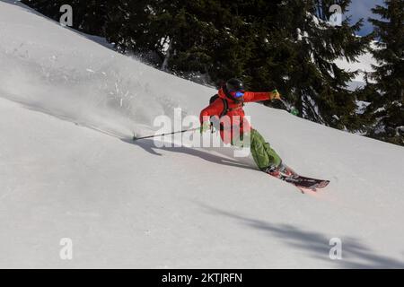 Skier skiing downhill during sunny day in high mountains, an adrenaline ...