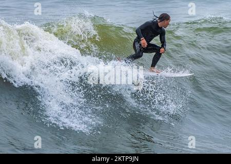Surfer riding a late autumn swell near the Jacksonville Beach Pier in ...