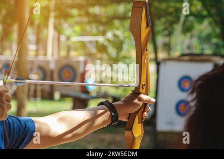 Hands of young man aims archery bow and arrow to colorful target in ...