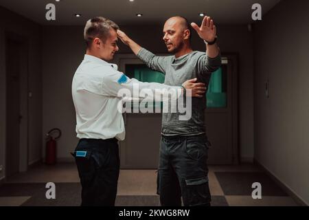 Security guard making body searching procedure with a metal detector on ...