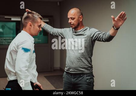 Security guard making body searching procedure with a metal detector on ...