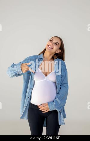 Young pregnant woman pointing to her big belly and looking happy Stock ...