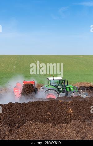 Turning a manure heap over to make compost to spread on farmland, which ...