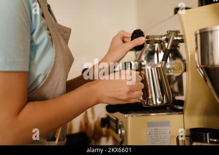 Asian barista woman wearing apron gesturing while working with cash ...