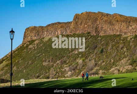 View of people clifftop ledge on Salisbury Crags, a rocky cliff in ...