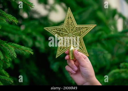 Christmas tree background Kid hand hangs decorating green Red ball toy ...