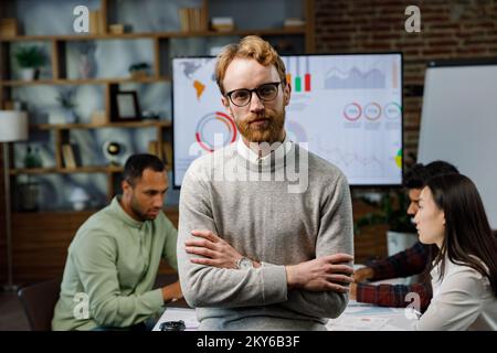 ginger team leader standing in front of the flipchart, pointing to it ...