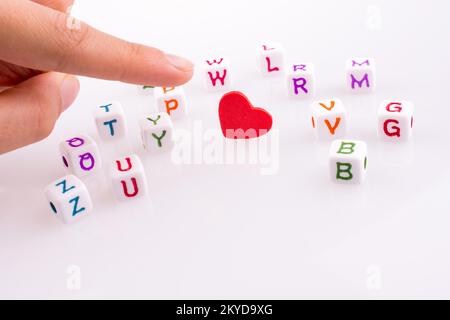 Hand pointing at Heart between Letter cubes on a white background Stock ...
