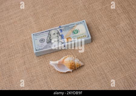 Sea shell placed on bundle of US dollar banknotes Stock Photo - Alamy