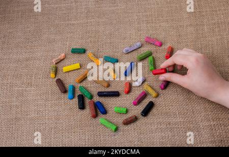 Hand holding a crayon by crayons forming a heart shape Stock Photo - Alamy