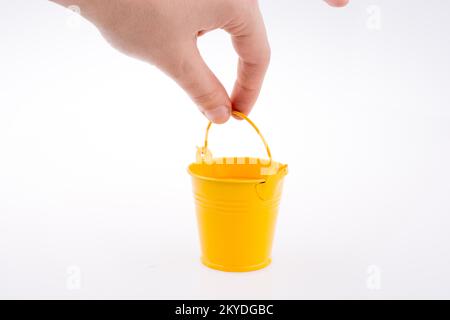 Hand holding a yellow bucket on a white background Stock Photo - Alamy
