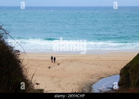 A couple on the beach at Porthcurno Bay, Cornwall, England, next the ...