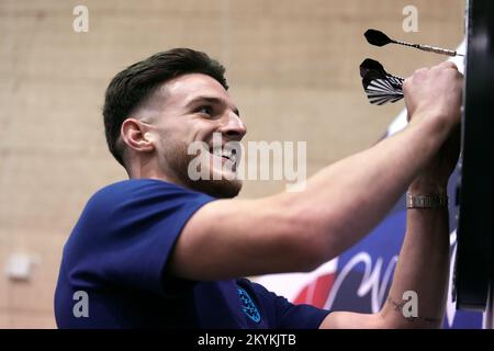 England's Declan Rice throws a dart during a game against a member of ...