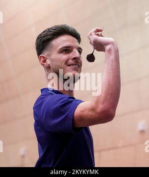 England's Declan Rice throws a dart during a game against a member of ...