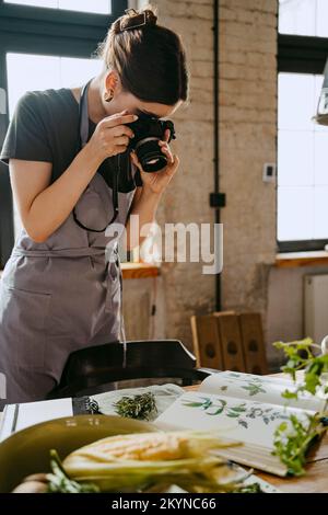 Young food stylist photographing through digital camera in studio Stock ...