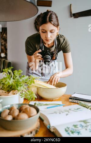 Young food stylist photographing through digital camera in studio Stock ...